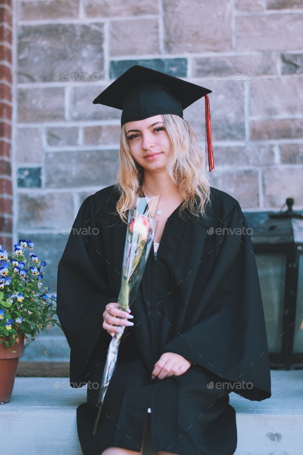 portrait of girl graduate sitting on front steps of house wearing ...