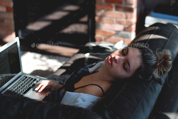Young teenage girl is taking a little nap, break, sitting on a couch ...
