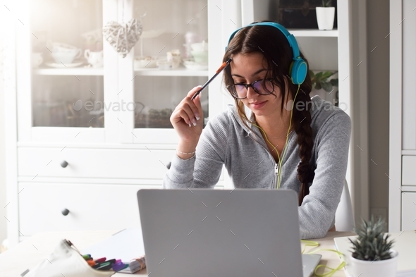 Young teenage girl student thinking while studying at home using laptop ...