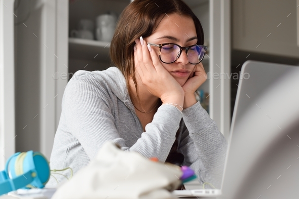 Young teenage girl falling asleep while studying or listening to online ...