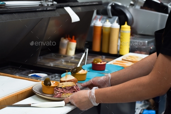 Restaurant kitchen employee working on preparing customer food order ...
