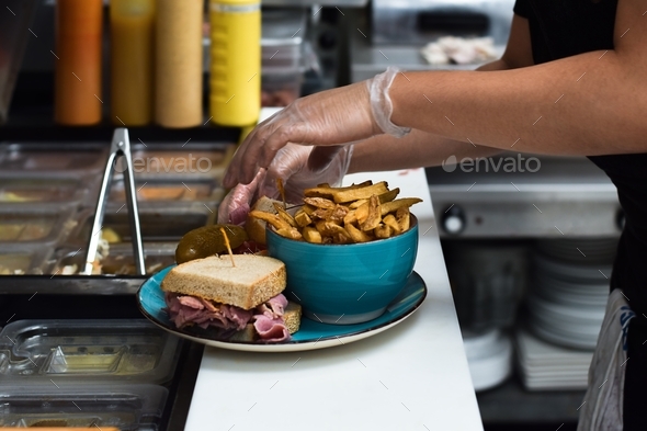 Restaurant kitchen employee working on preparing customer food order ...