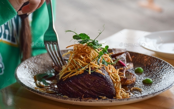 Girl eating short rib dish at a restaurant Stock Photo by JulieAlexK