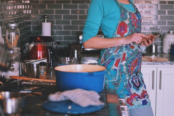 Woman is checking a recipe on her mobile phone while cooking dinner in ...
