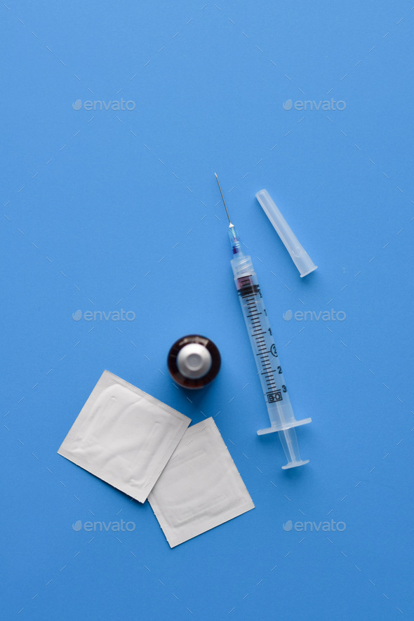 Syringe, a medication vial and alcohol wipes for an injection on blue ...