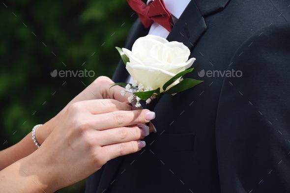 A girl is attaching a boutonniere to a boy’s jacket. Couples at a ...