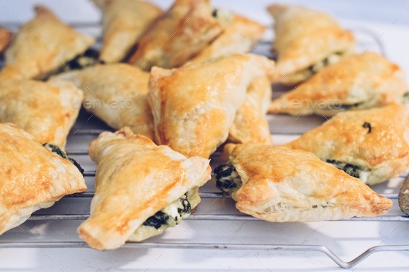 Triangle pastries with feta and spinach cooling on a rack Stock Photo ...