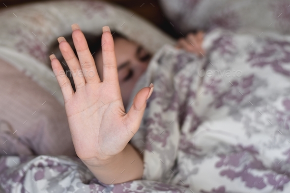 Young girl laying in bed sleeping, extending her hand not to be ...