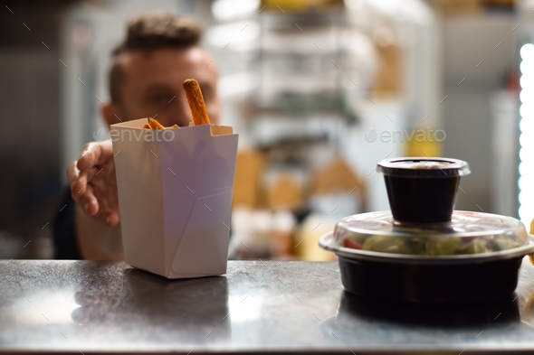 Restaurant kitchen employee is placing take out food order in a window ...