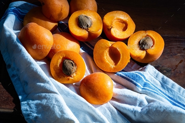 halved ripe raw apricots with seeds inside Stock Photo by MarieKazalia