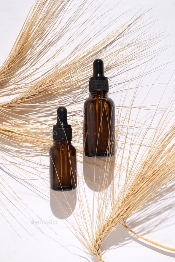 Amber glass dropper bottles different sizes and ears of barley on white ...