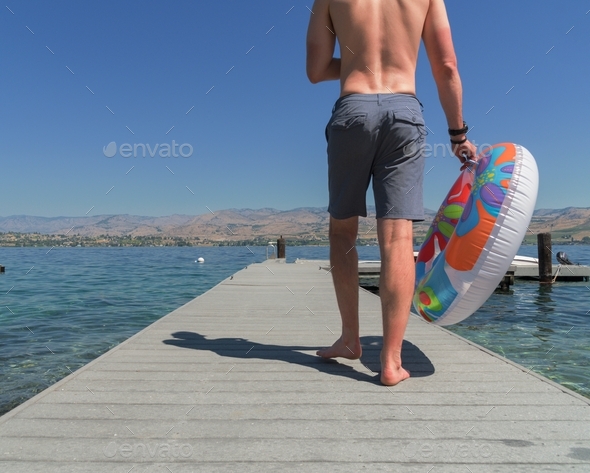 Man walking with his floatation inner tube on lake dock Stock Photo by ...
