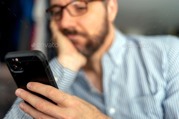 Bored man scrolling on his smart phone Stock Photo by RLTheis | PhotoDune
