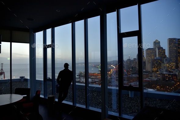 Silhouetted person enjoying view from inside large windows overlooking ...