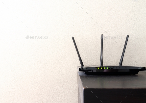 Wifi router with 3 antenna on corner of desk. Stock Photo by RLTheis