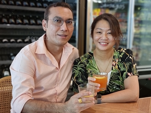 Malaysian couple enjoying a drink at the restaurant Stock Photo by weewendy
