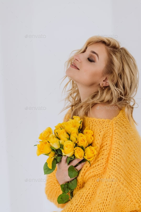 Portrait of a beautiful young blonde woman with a bouquet of yellow ...
