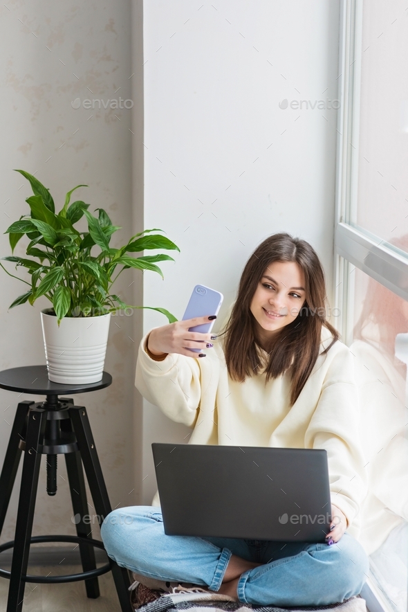 Smiling young teenage girl video calling on mobile phone, talking to ...