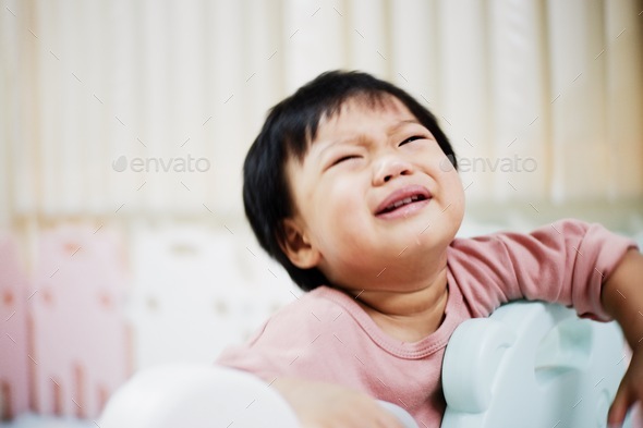 Portrait of sad baby crying alone in bedroom Stock Photo by Jsttanrak