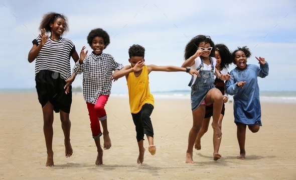 Children or kids playing and romp together at the beach on holiday ...