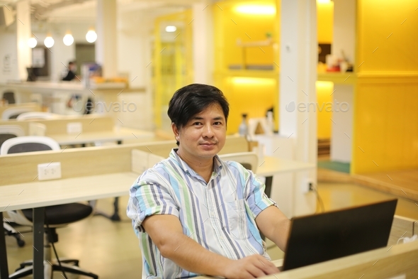 young Asian freelance designer smiling while look at camera against ...