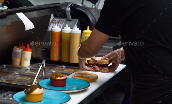 Restaurant kitchen employee working on preparing customer food order ...