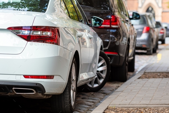 rows of different cars parked along the roadside in crowded city Stock ...