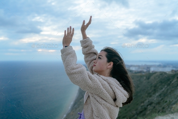 girl trying to touch the sky with her hands Stock Photo by senencov