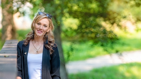 fashion portrait of a elegant, nice, smiling blonde woman on a defocused park background Stock ...