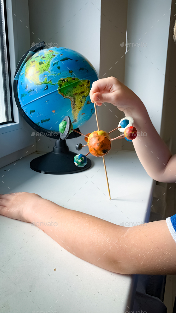 The child holds in his hands a model of the solar system, which he ...