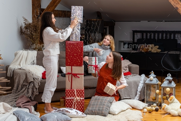 young girls having fun wrapping gifts at home, teamwork of friends ...
