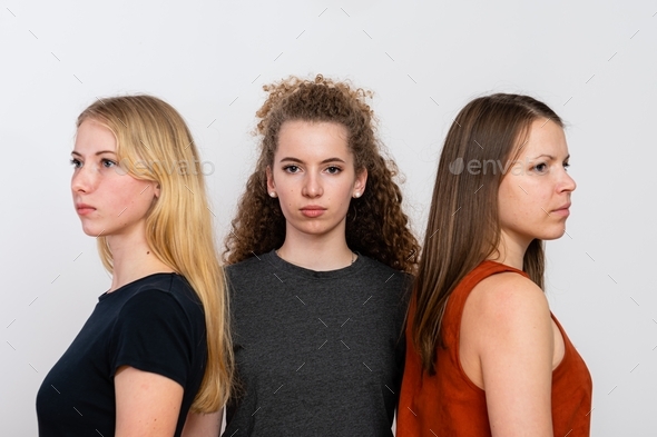 three sisters of different ages standing against each other, group ...