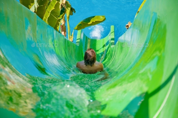 Man sliding going down on a water slide in the pool. Summer travel ...