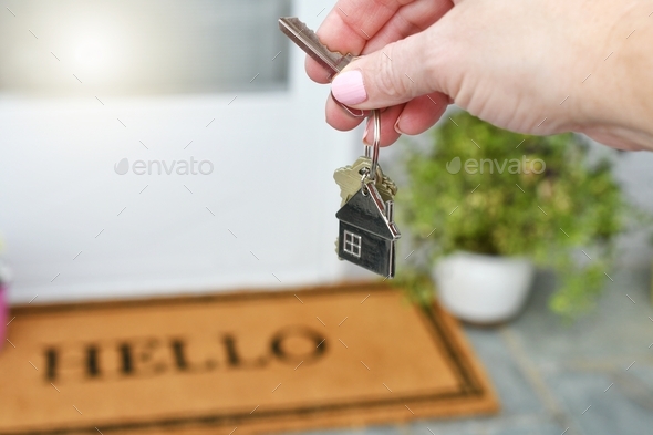 Dangling a set of keys to a front door on the porch with HELLO welcome ...