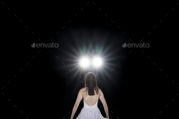View of a woman in a white dress from behind looking into two bright ...