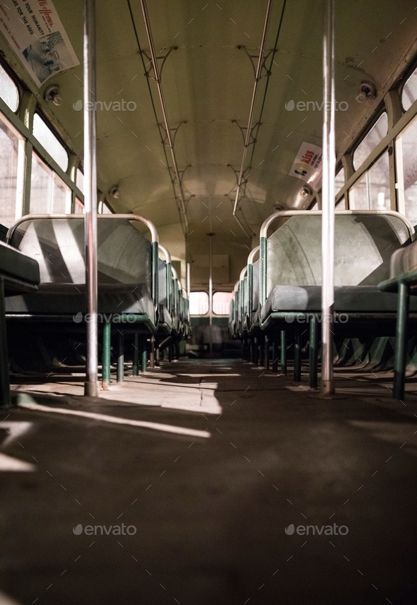 View down the empty isle of a bus with rows of seats at night, light ...