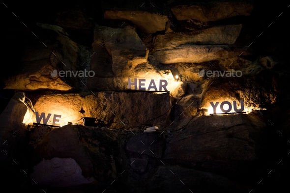 We hear you signage against dark rock indoor cave back lighting art ...