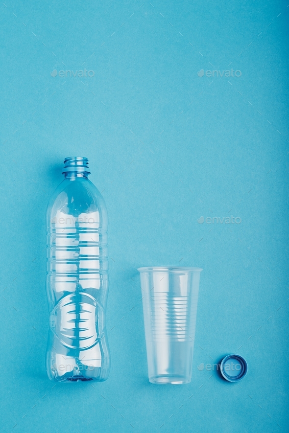 Empty plastic bottle, cup and cap over blue background. Collecting ...