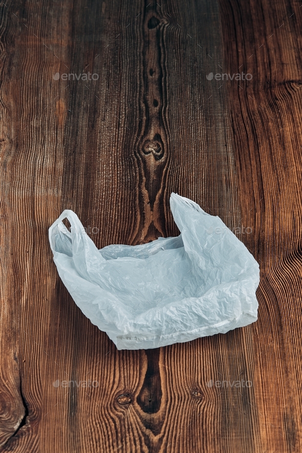 White empty plastic bag over wooden background. Plastic pollution ...