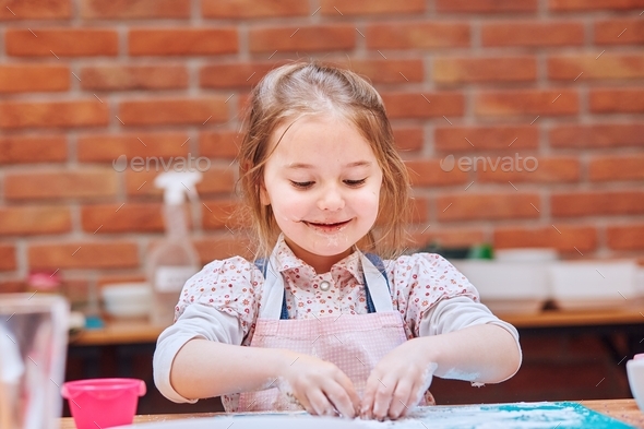 Little girl eating the icing sugar left after baking cookies Stock ...