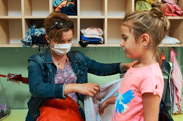 Child little girl changing clothes in changing room in nursery school ...