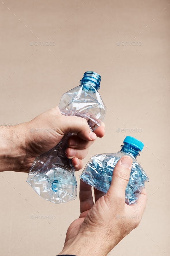 Male hand holding squashed plastic bottle over paper background Stock ...