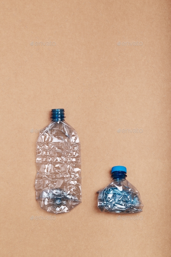Squashed empty plastic bottles put in a row, over cardboard background ...