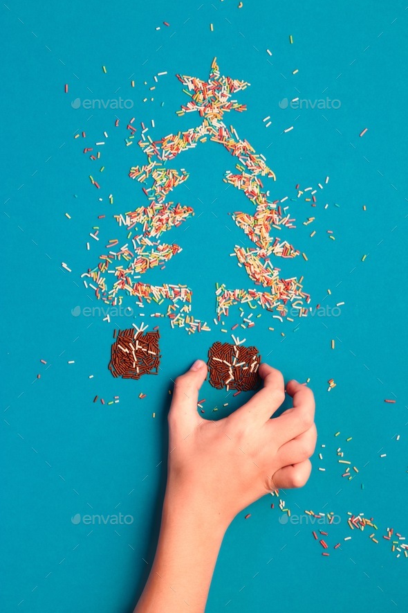 Funny playing with sprinkles. Girl making symbols of Christmas tree and ...