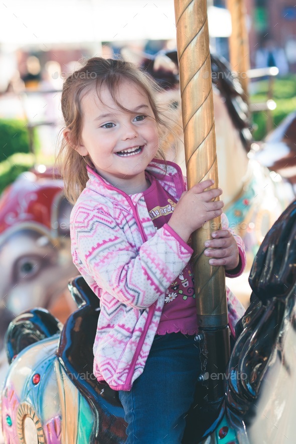 Funfair. Little girl riding a horse on roundabout carousel at funfair ...
