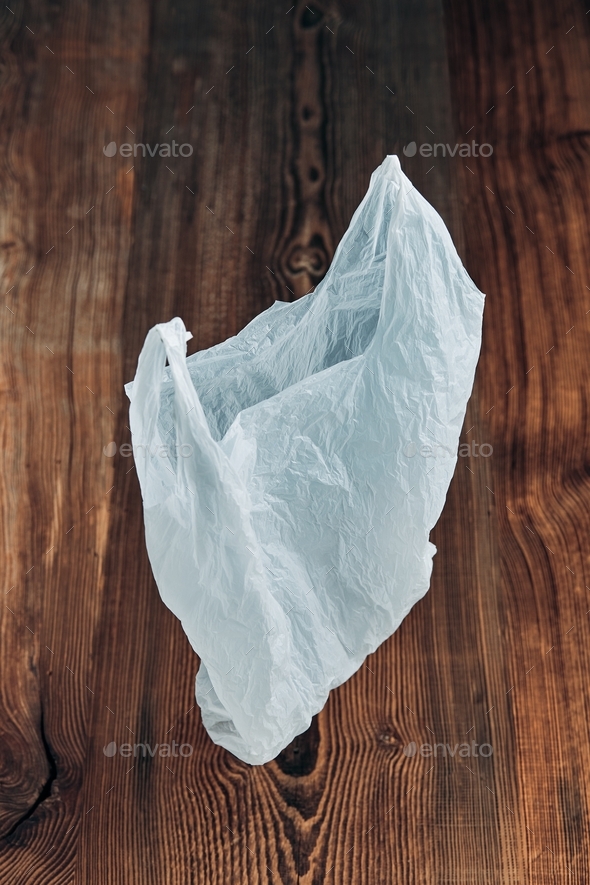 White empty plastic bag floating over wooden background. Plastic ...