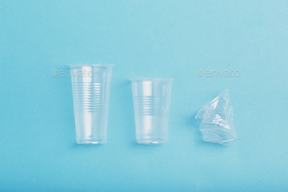 Plastic cups put in row, over blue background. Collecting plastic waste ...