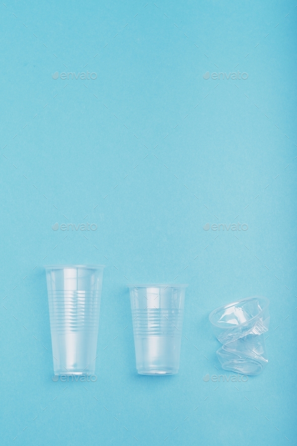 Squashed empty plastic cups put in a row, over blue background ...