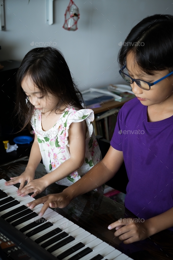little girl with brother playing keyboard musical instrument together ...