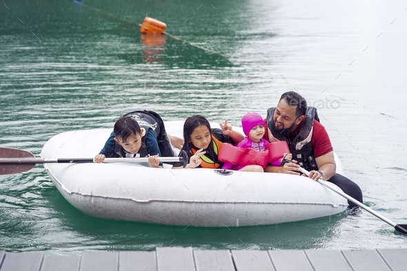 family on an inflatable boat, having fun in a lake Stock Photo by ellinnur